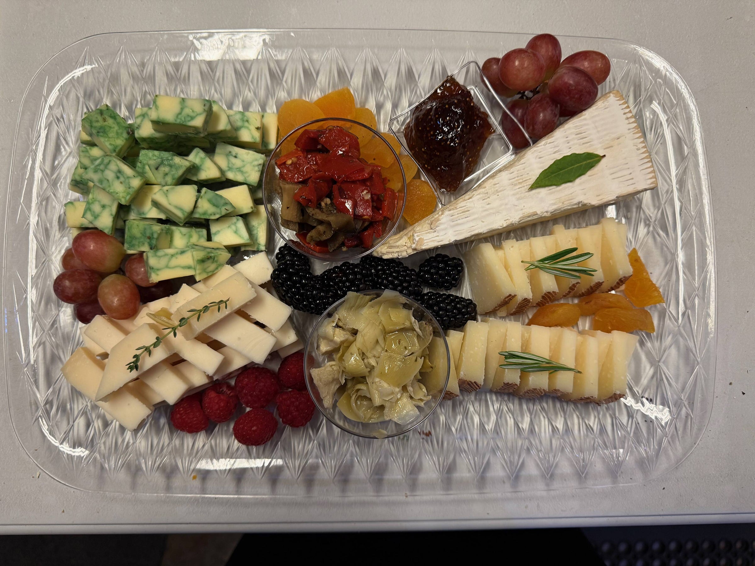 A clear platter with an assortment of cheeses, including sage derby ...
