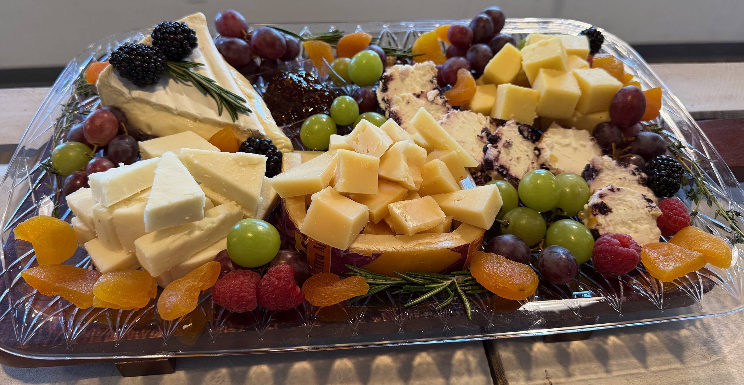 A colorful cheese platter featuring cubed and sliced cheeses, blueberry ...